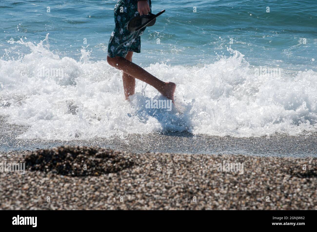 Walking through splashing waves on a beach in Greece Stock Photo - Alamy