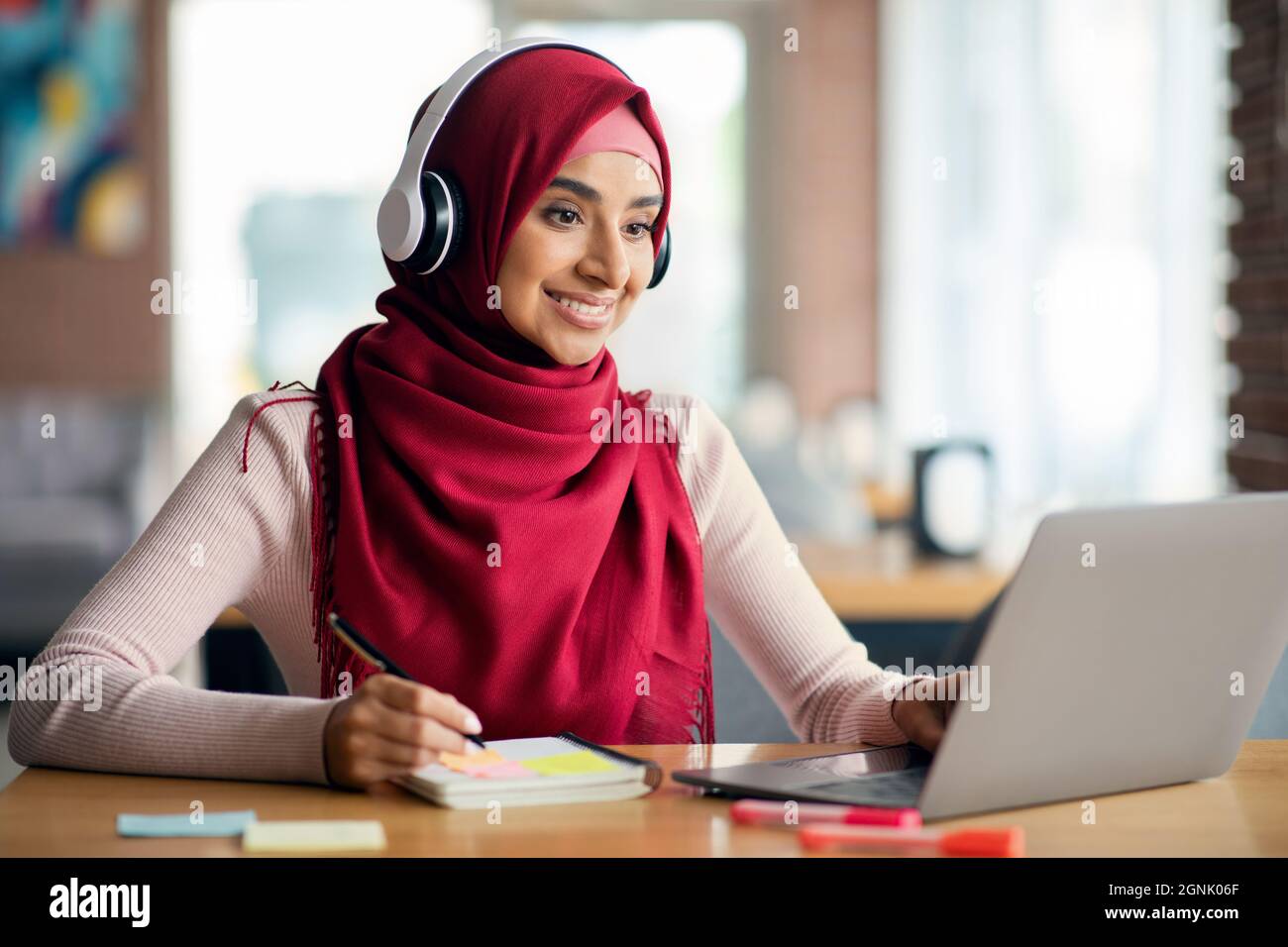Joyful muslim woman attending online class, cafe interior, copy space ...