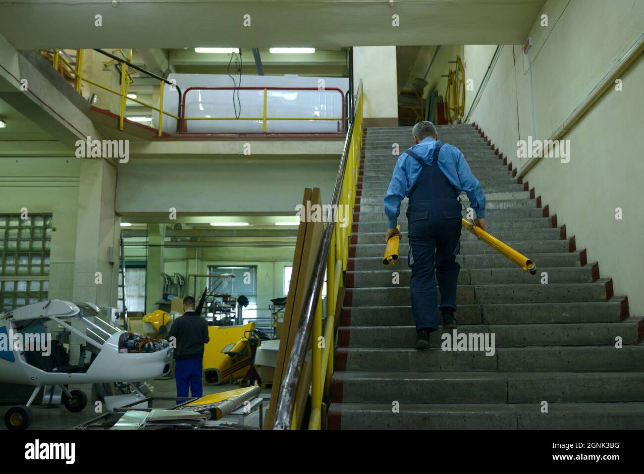 The assembly shop. Worker going up stairs carrying parts of a body ...