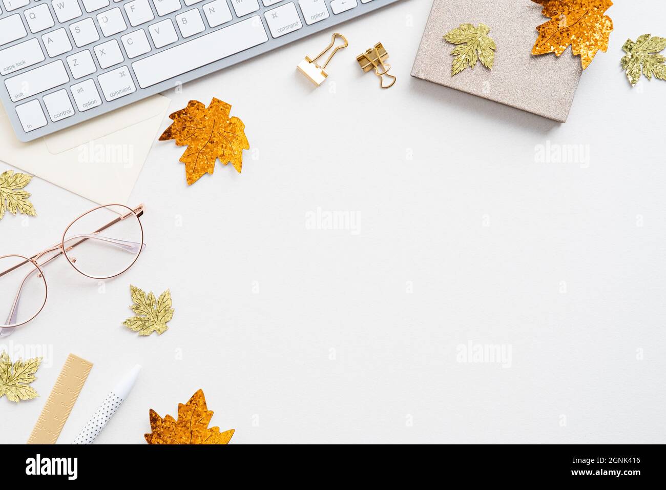 Autumn desk table with golden maple leaves, keyboard, female glasses on ...