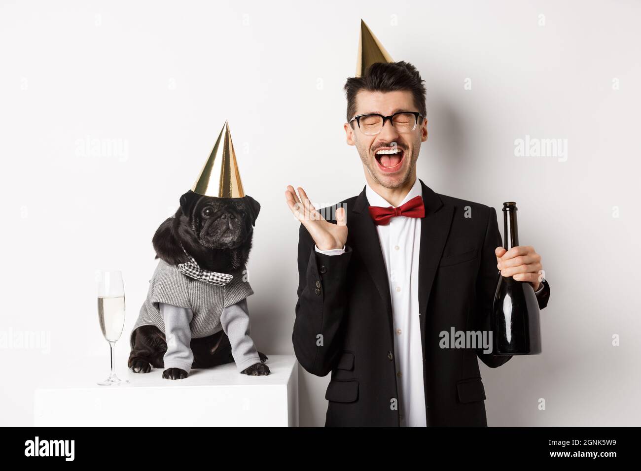 Happy young man celebrating holiday with cute dog, holding champagne ...