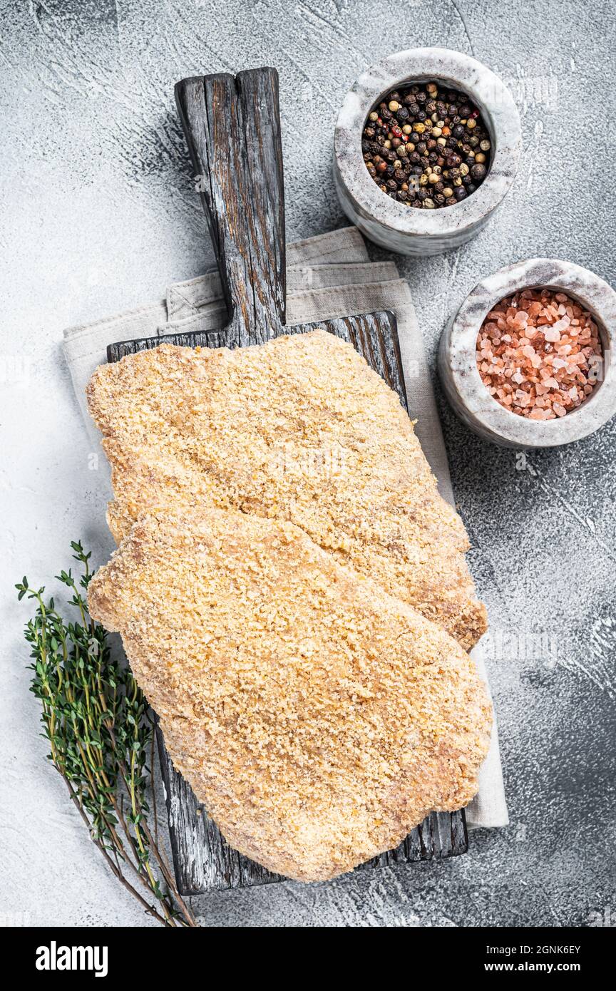 Wiener Raw schnitzel in breadcrumbs on wooden board. White background ...