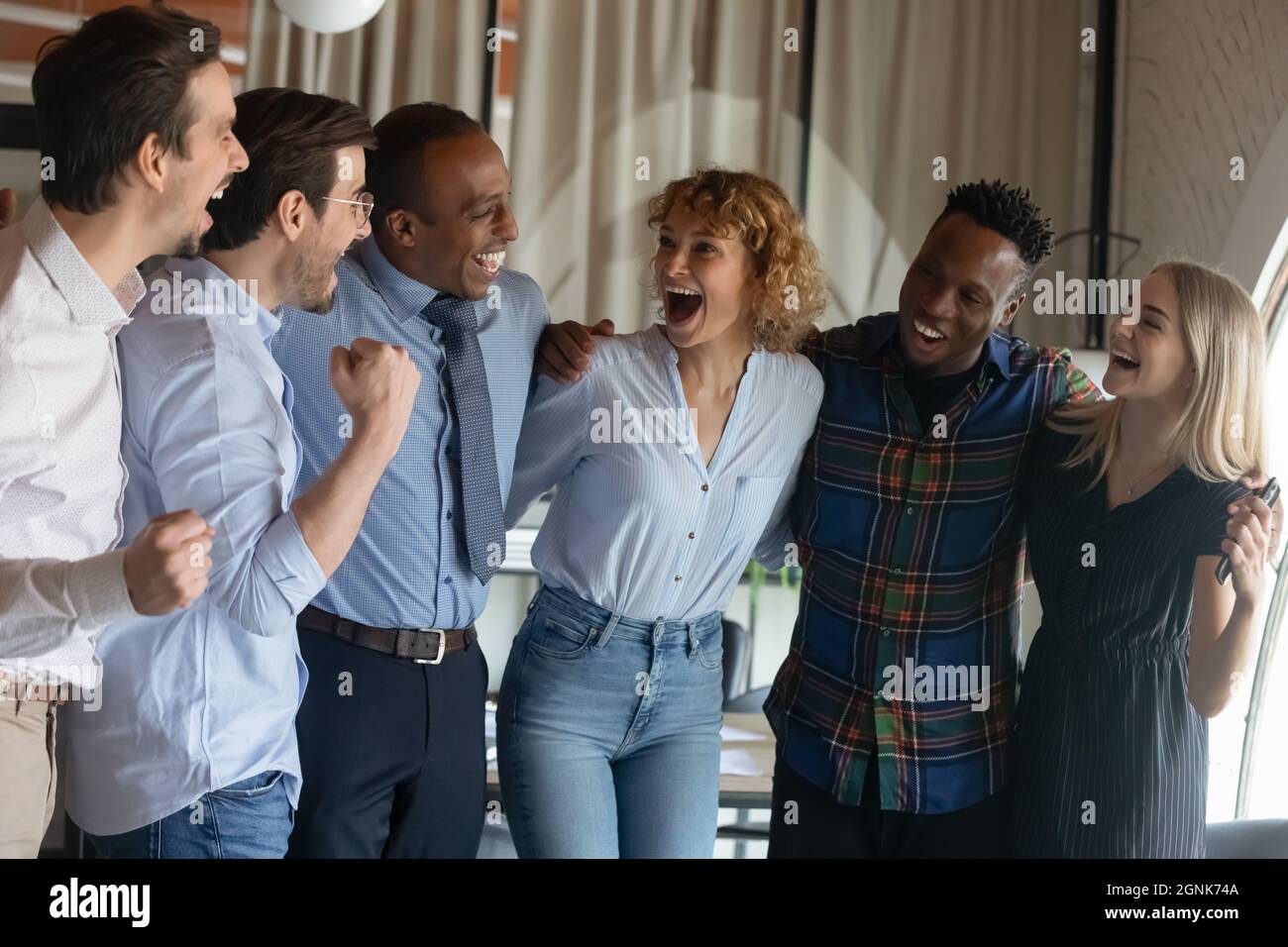 Group of happy excited diverse employees hugging, shouting for joy ...