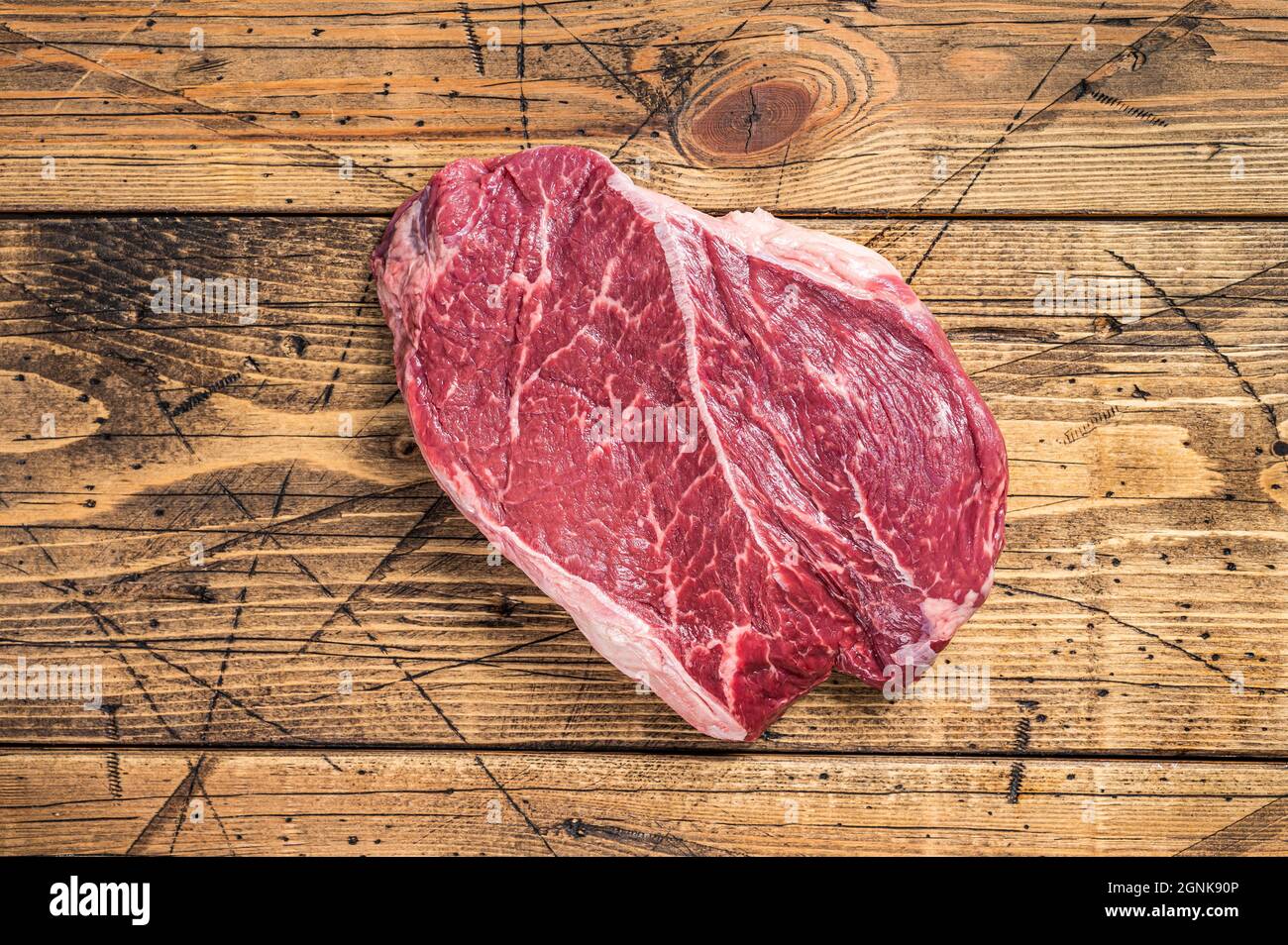 Dry aged raw beef round steak cut on a butcher table. wooden background ...