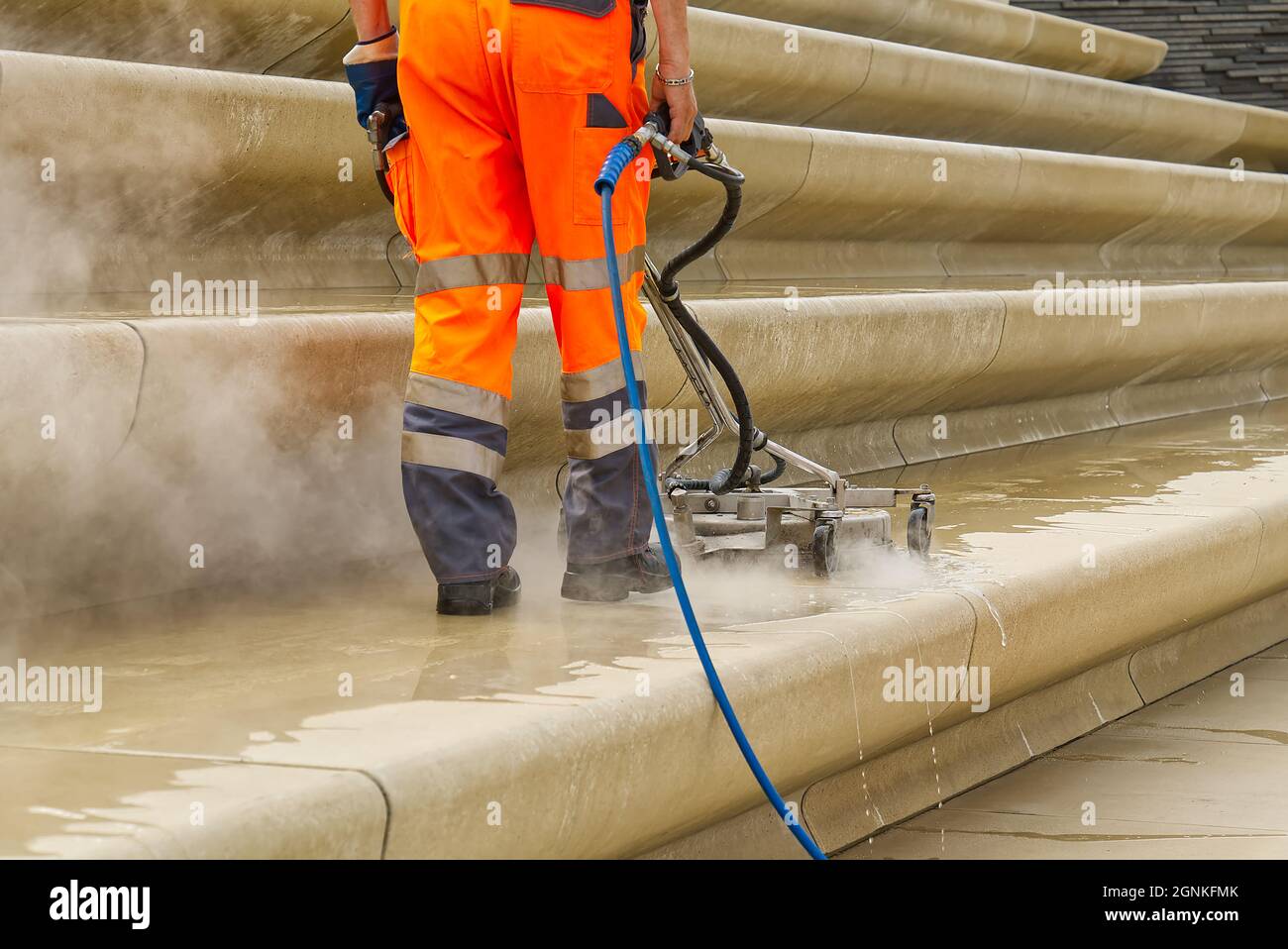 worker washes the pavement. Worker in uniform washes street with street ...