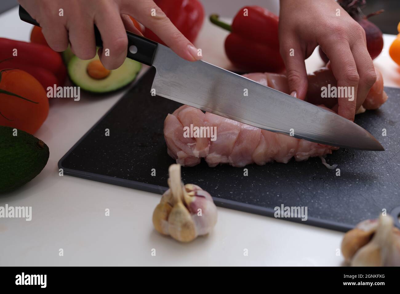 Woman hand cuts meat fillet with knife on board next to garlic Stock ...