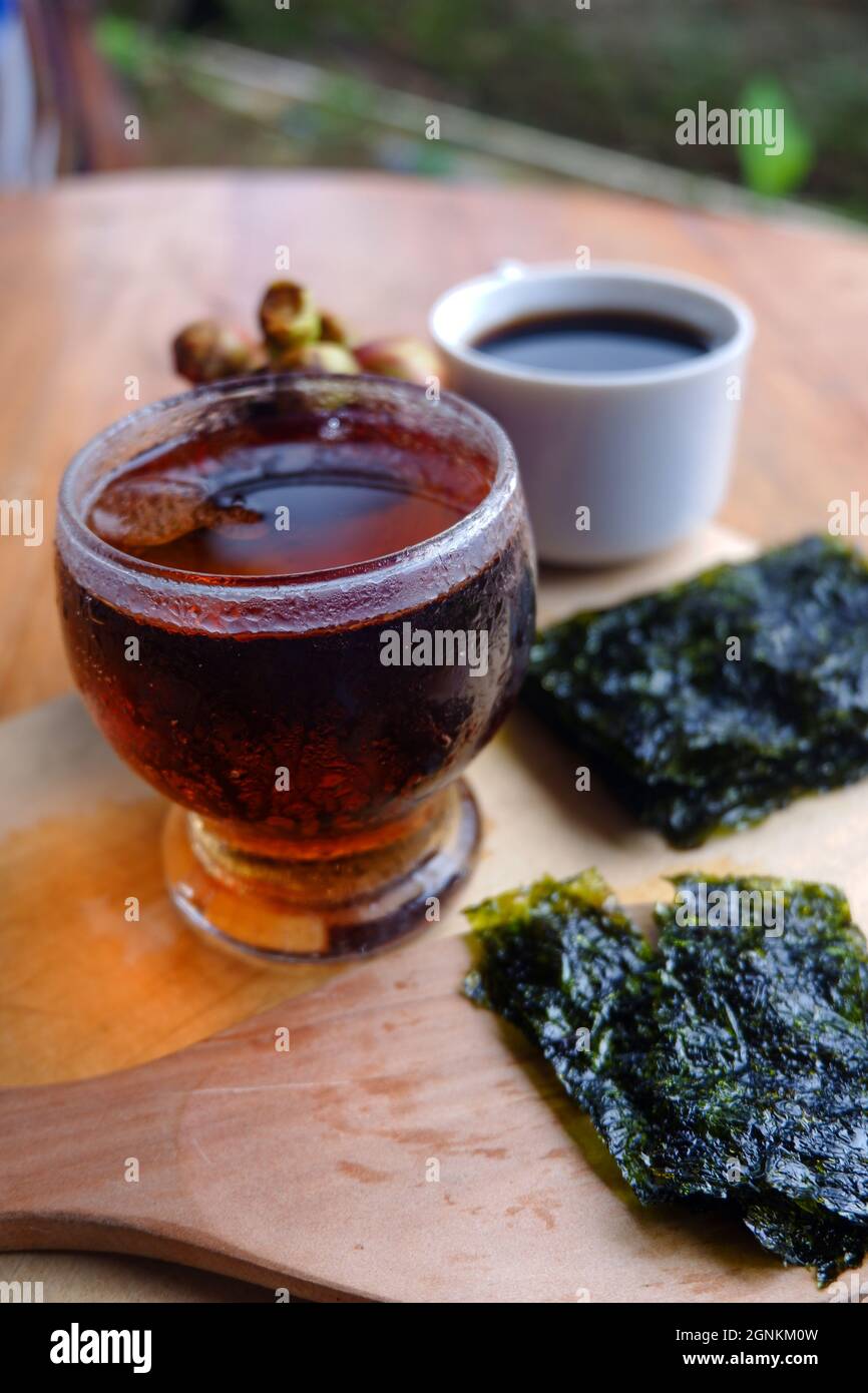 The chopped seaweed and a cup of iced coffee on the wooden table Stock ...