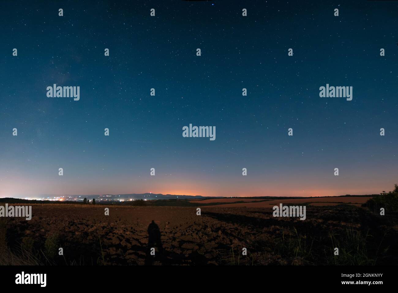 Panoramic night landscape with crop agricultural fields and city lights ...