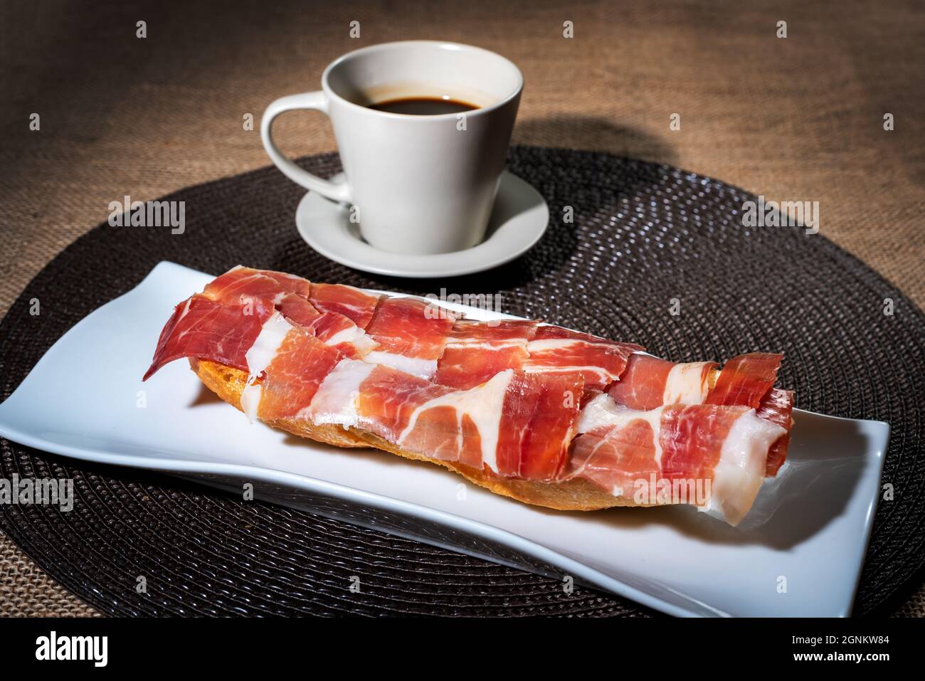 Breakfast consisting of a coffee and a Serrano ham toast with olive oil ...