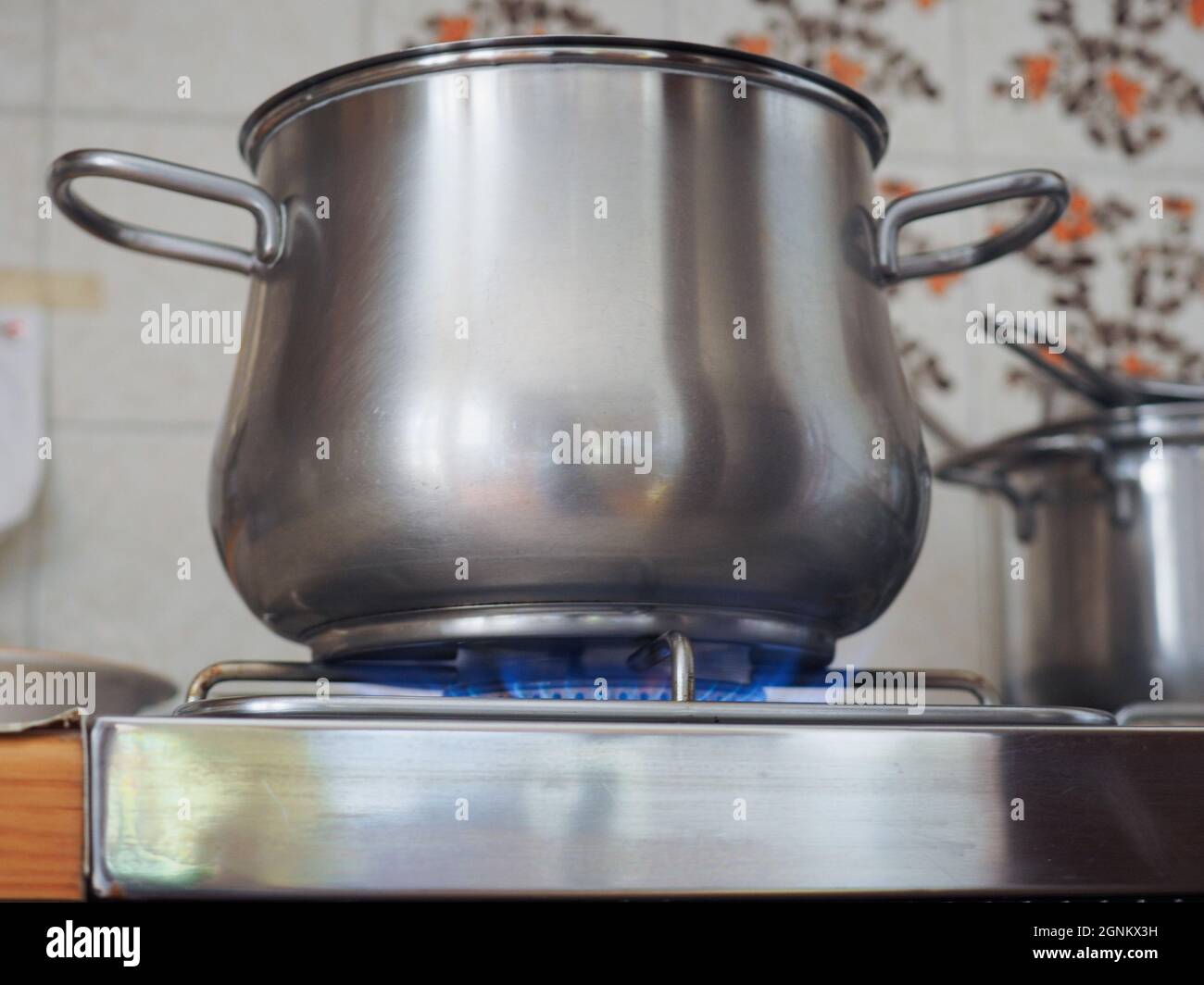 steel pot on a burner with blue gas flame Stock Photo - Alamy