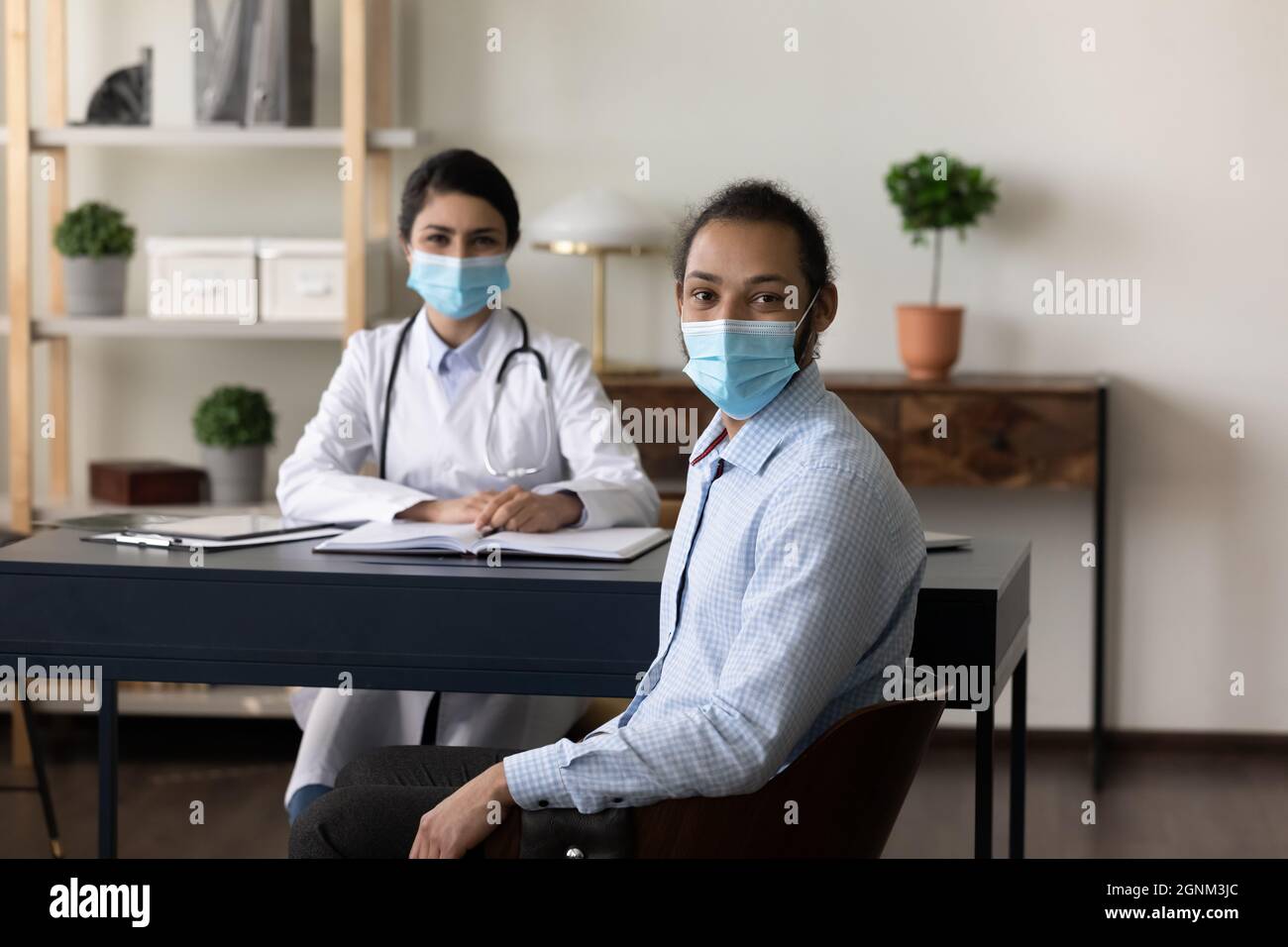 Happy multiethnic female doctor and male patient wearing face masks ...