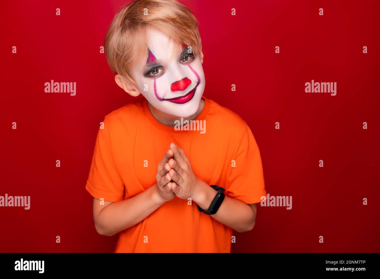 sly boy with halloween makeup put his palms together in front of him ...