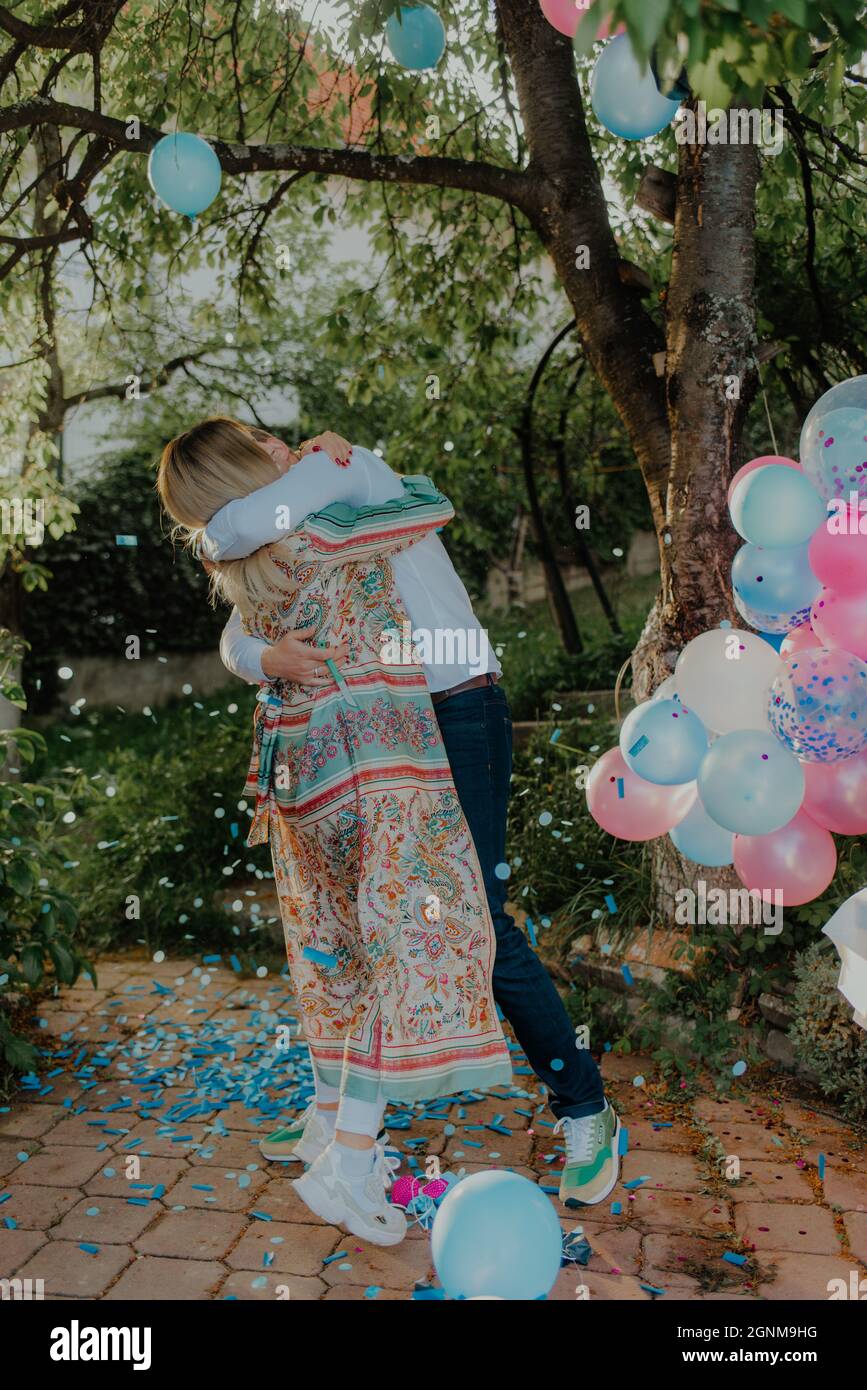 A couple hugging during the baby gender party Stock Photo - Alamy