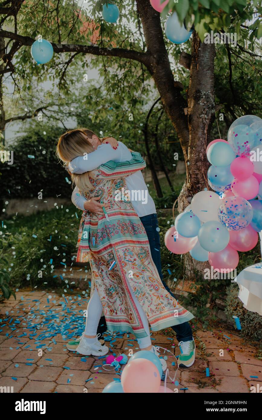 A couple hugging during the baby gender party Stock Photo - Alamy