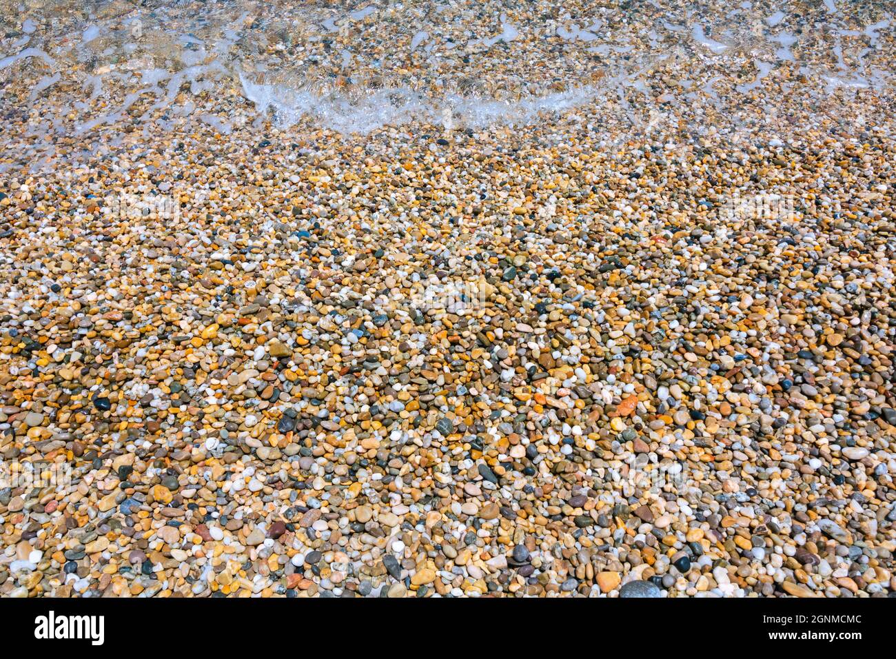 Small pebbles on the shore in a beach with wavy sea. Summer background ...