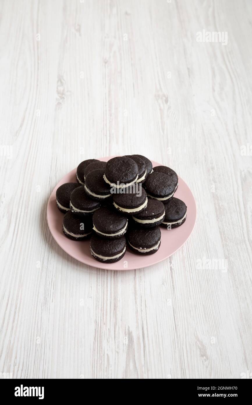 Homemade Oreos on a pink plate on a white wooden background, side view ...