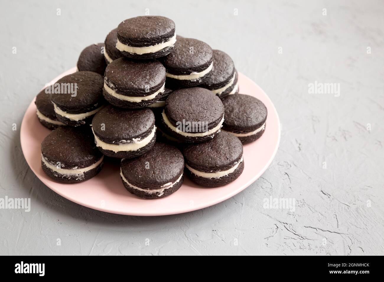 Homemade Oreos on a pink plate on a gray background, side view. Space ...