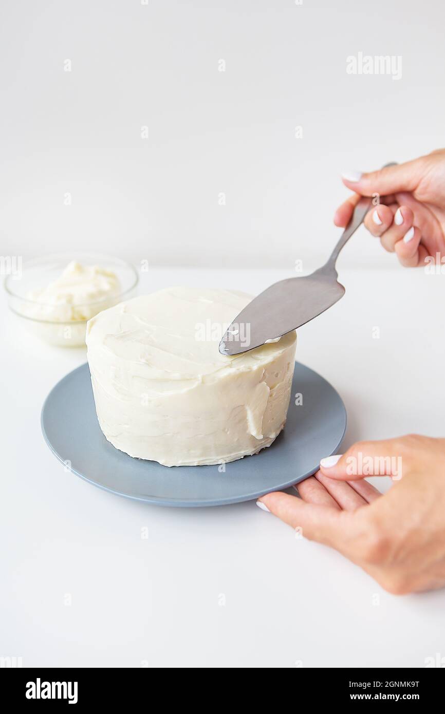 Delicious creamy cake that the girl spreads over the whipped cream with ...