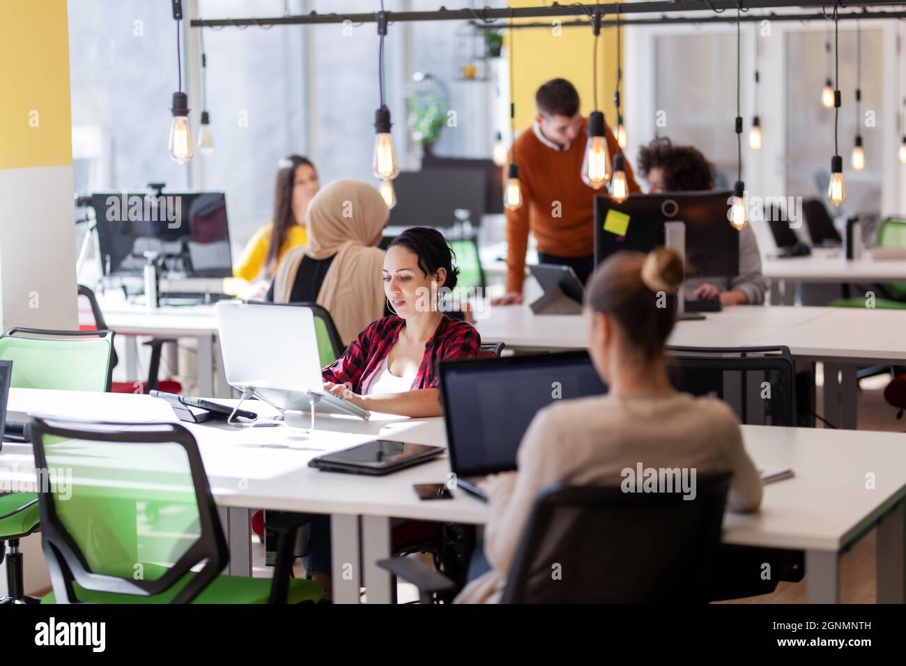 Creative team of young individuals working on desktop computers in a ...