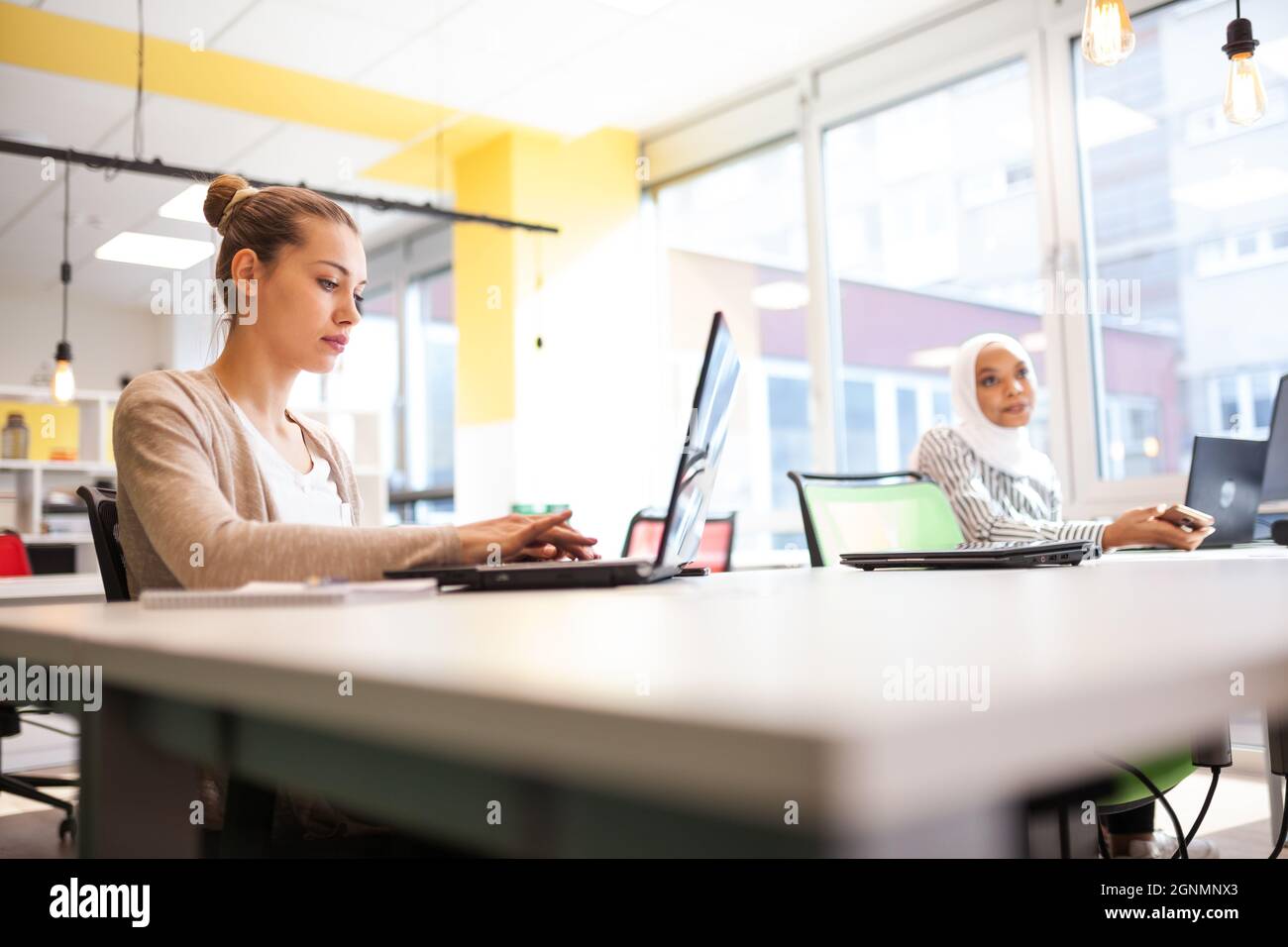Beautiful girl working on a laptop in a modern coworking space ...