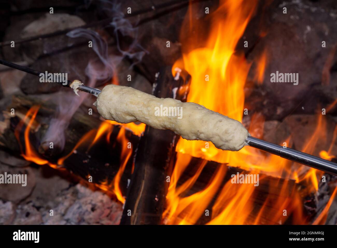 Baking of stick bread on the camp fire Stock Photo - Alamy