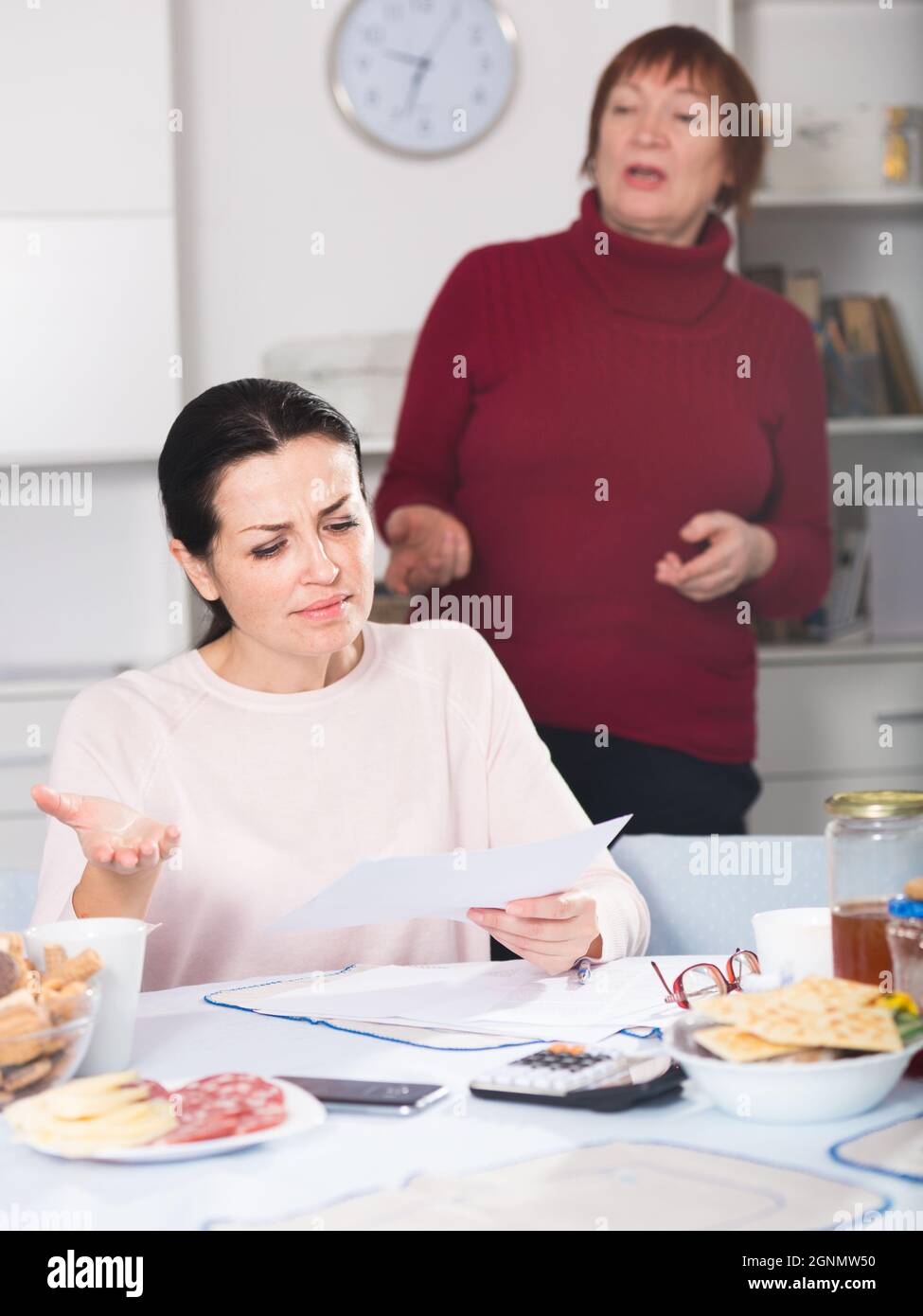 Young woman and mother with financial documents, quarrel Stock Photo ...