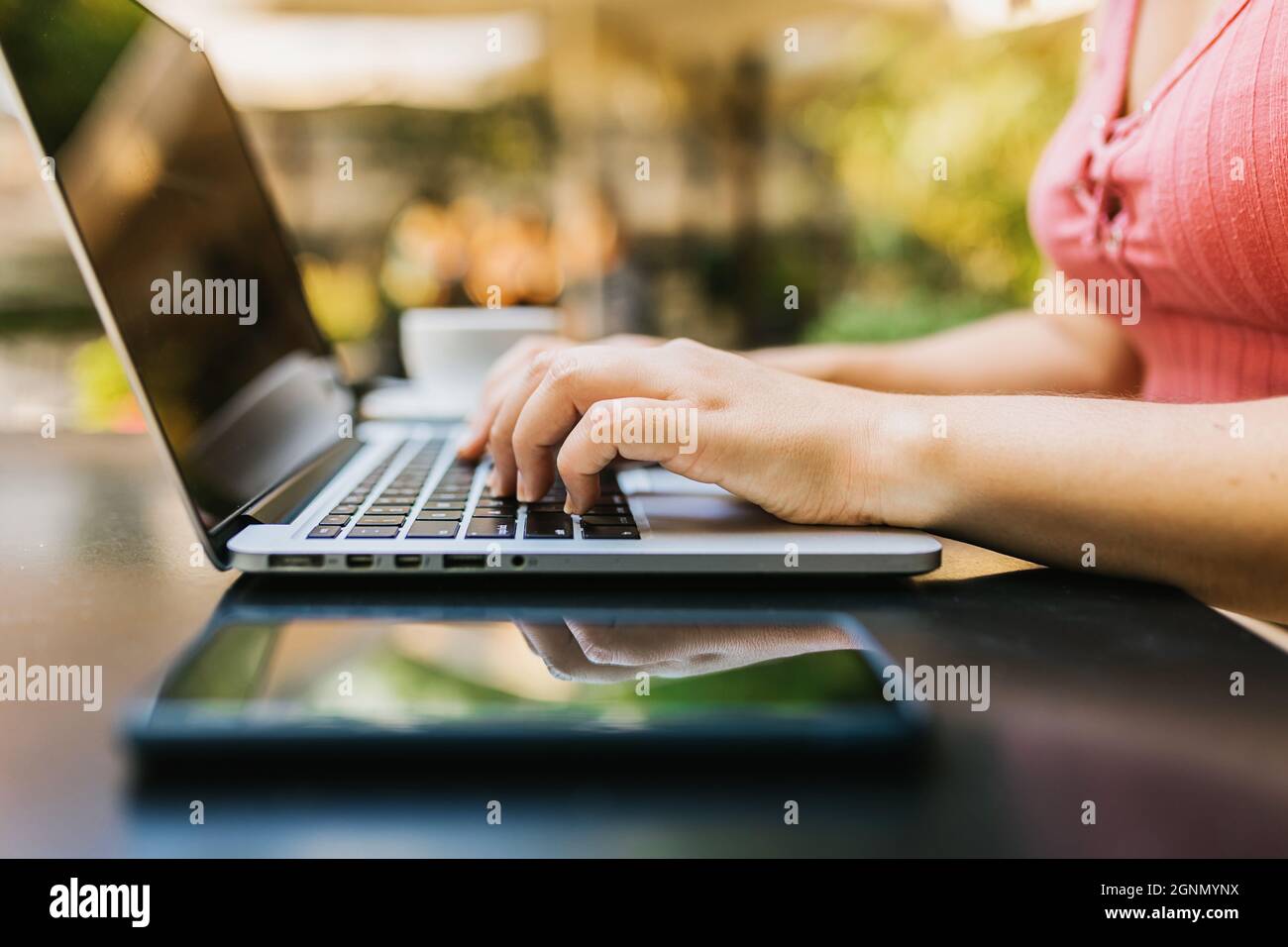Side view woman hands working on laptop while sitting at terrace cafe ...