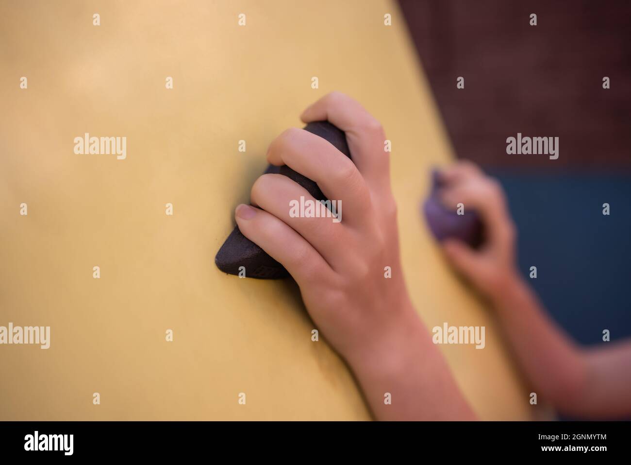 Yellow climbing wall with colorful rocks playground Stock Photo - Alamy