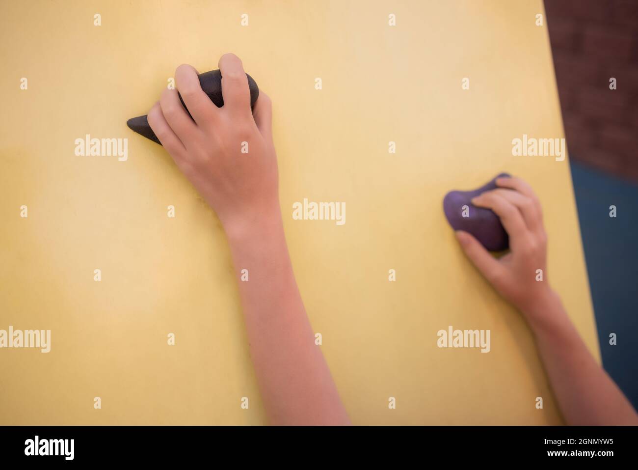 Yellow climbing wall with colorful rocks playground Stock Photo - Alamy