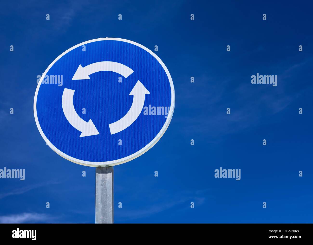detail of a roundabout sign over a blue sky Stock Photo - Alamy