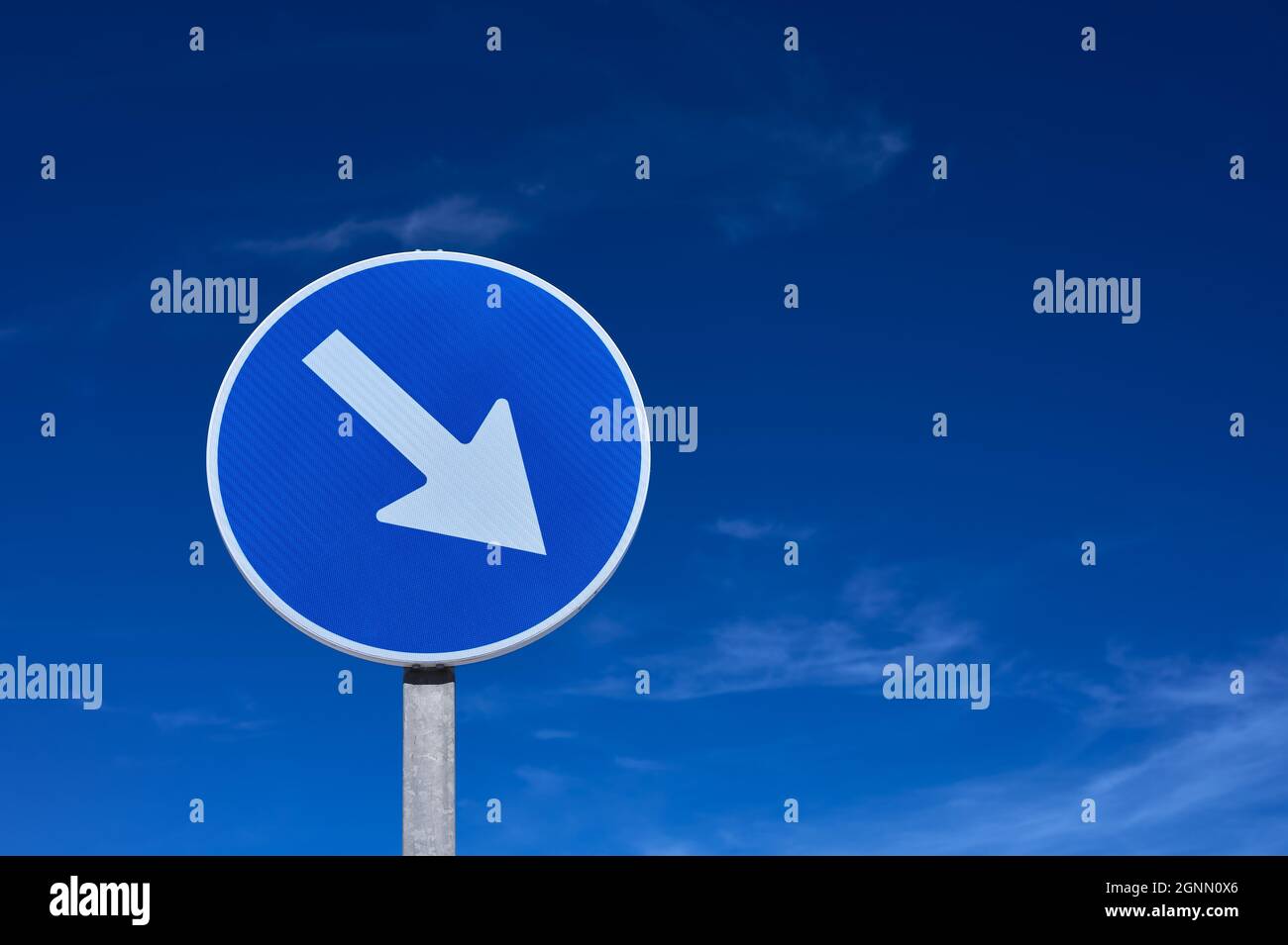 detail of a traffic sign indicating to keep to the right against a blue ...