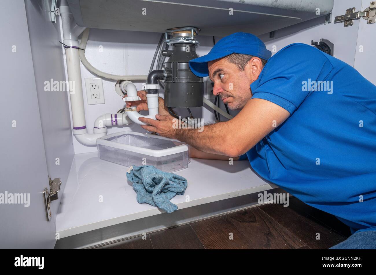 Professional plumber working on pipes under a kitchen sink Stock Photo ...