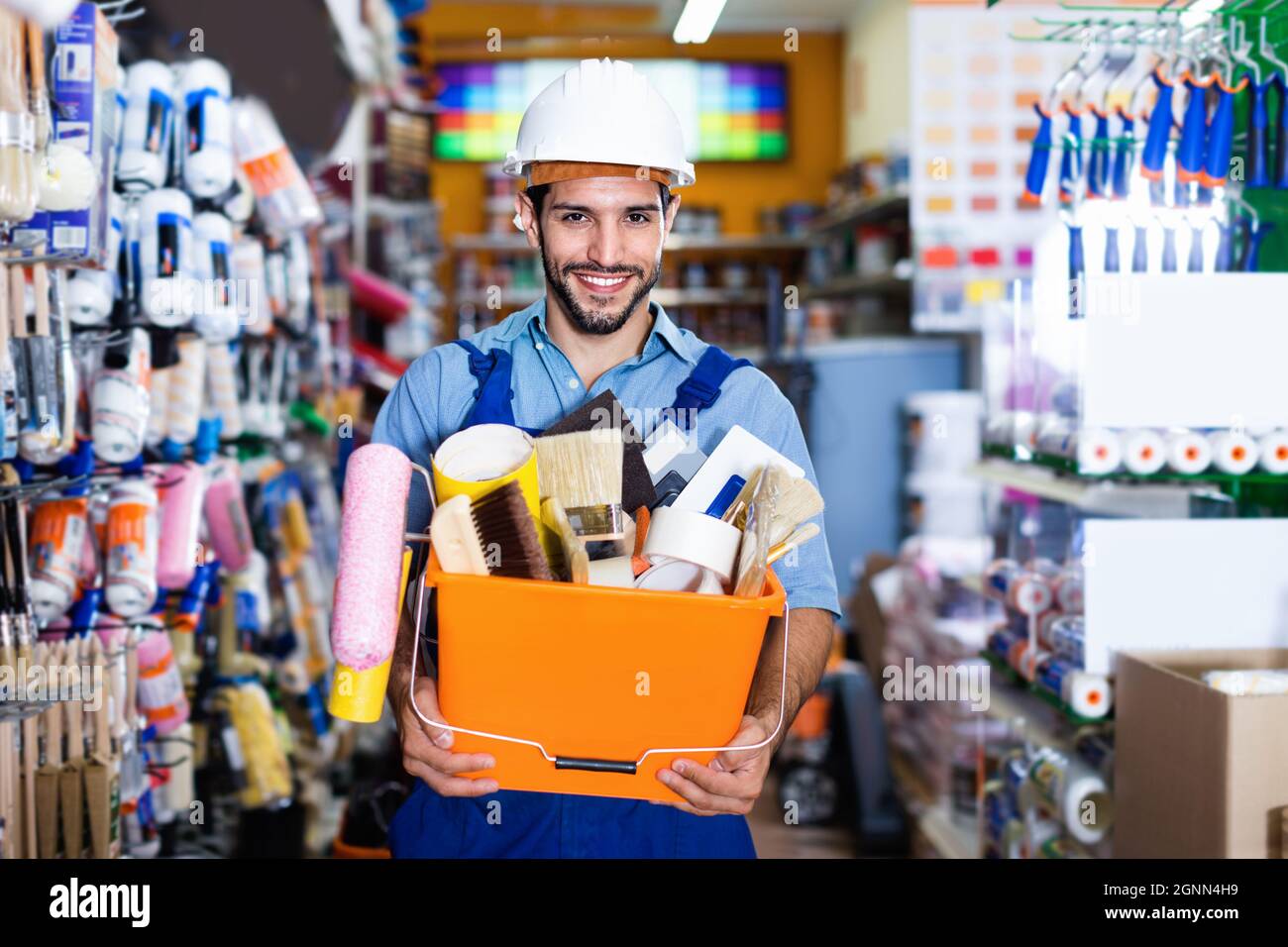 Workman holding basket with picked tools in paint store Stock Photo - Alamy