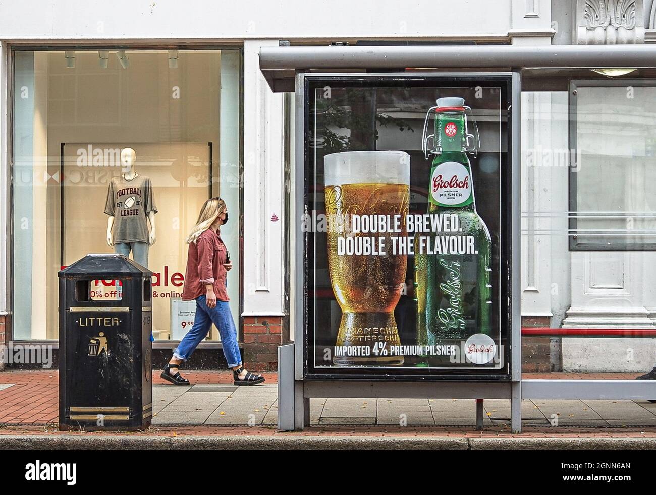 A shopper walks by Grolsch Lager advertising on bus shelter on Royal ...