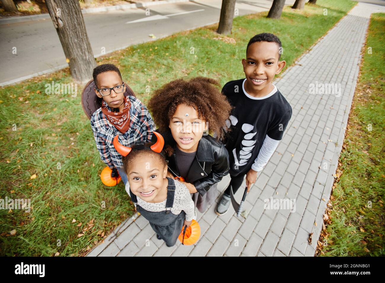 Group of smiling African-American kids trick or treating outdoors and ...