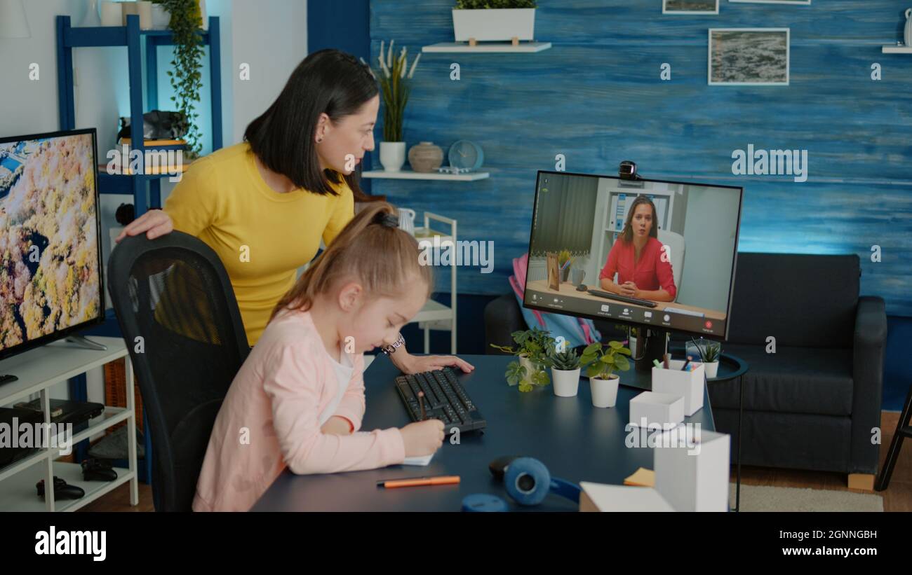 Child and mother using video call with teacher for online lesson and ...
