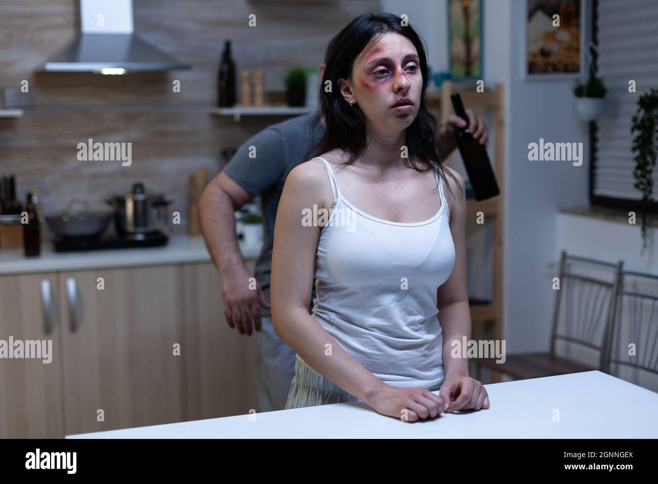 Abused woman sitting in kitchen with drunk husband dealing with ...