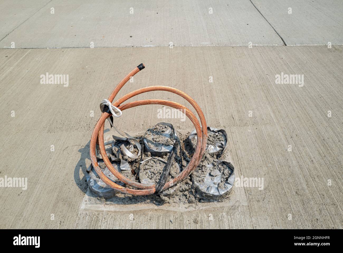 Coiled copper wire is sticking out of concrete on the ground Stock ...
