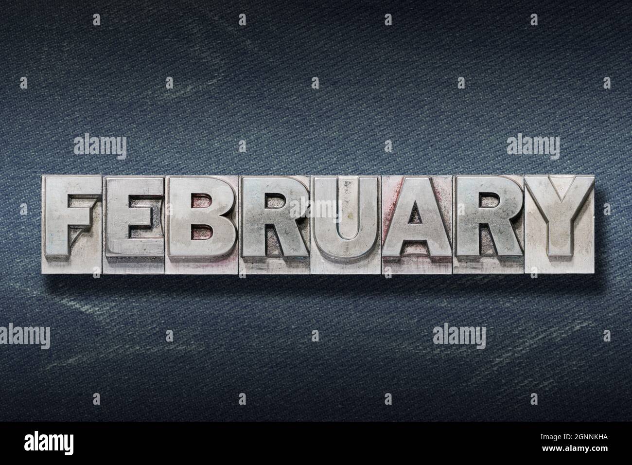 February word made from metallic letterpress on dark jeans background ...