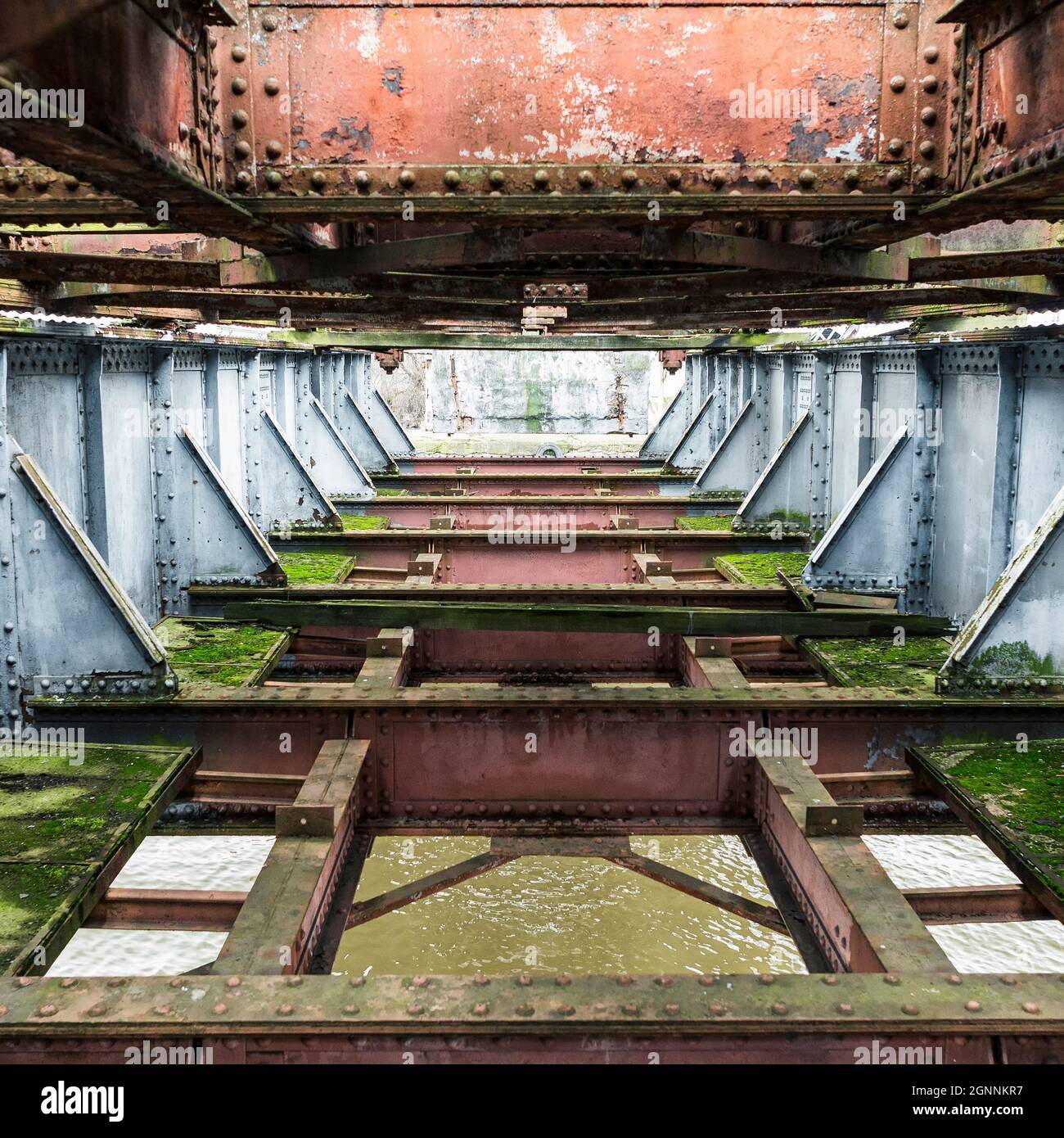 Rusted metal structure of an old railway bridge, covered with moss ...