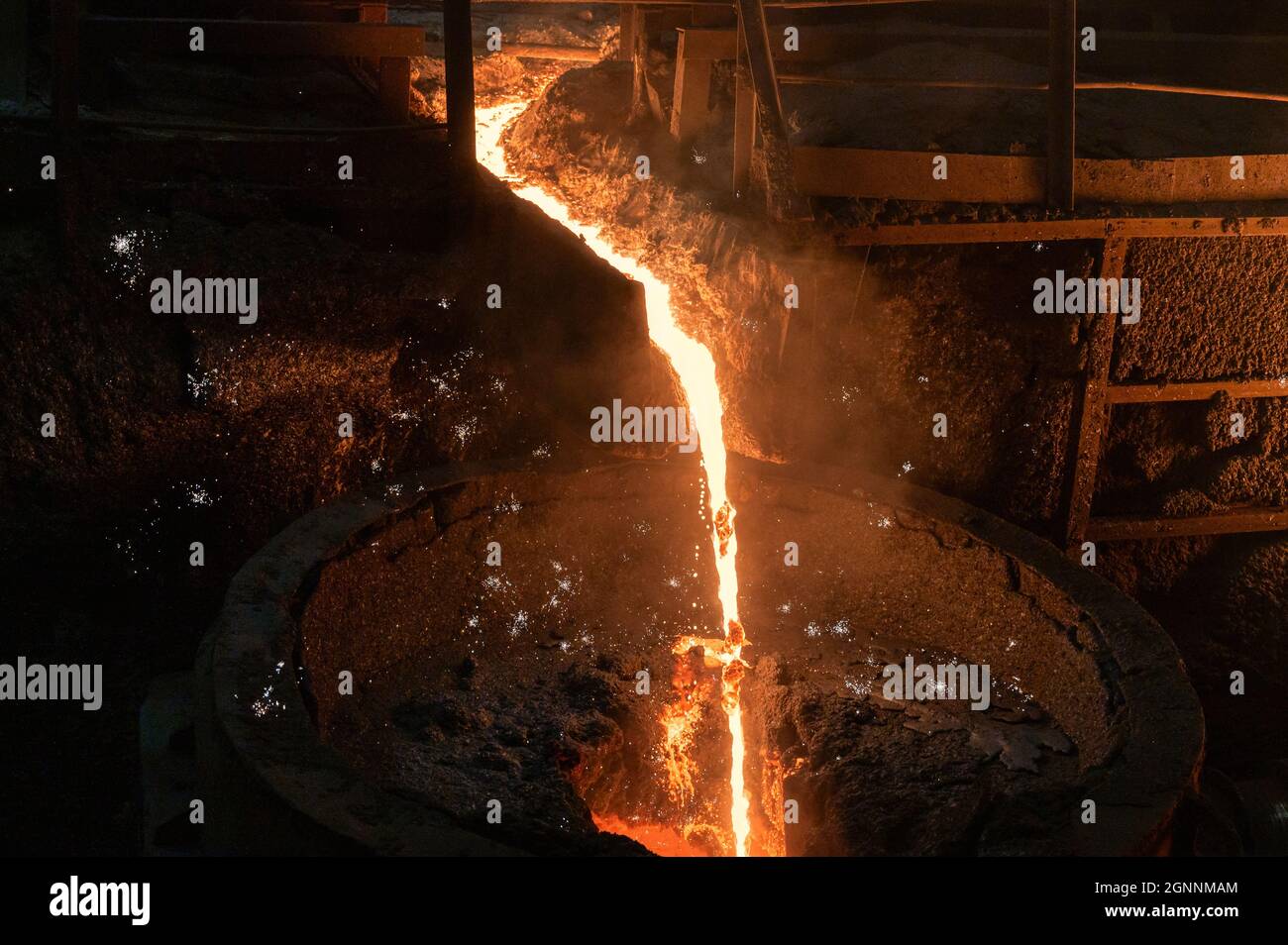 Molten iron. Liquid metal is poured into the ladle in a thin stream ...