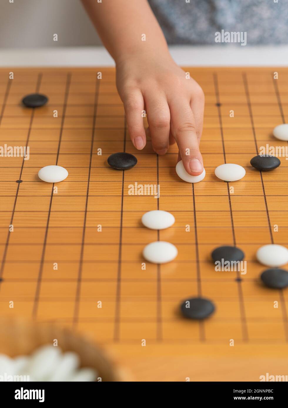 Child hand playing Go board game, white and black stones on the board ...