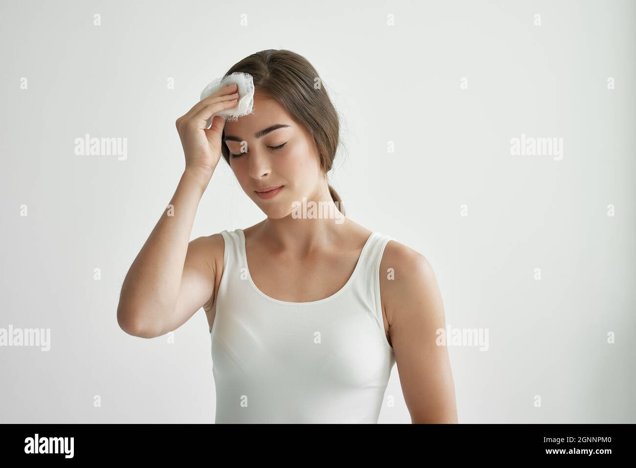 woman in white t-shirt wipes her forehead with a handkerchief pain head ...