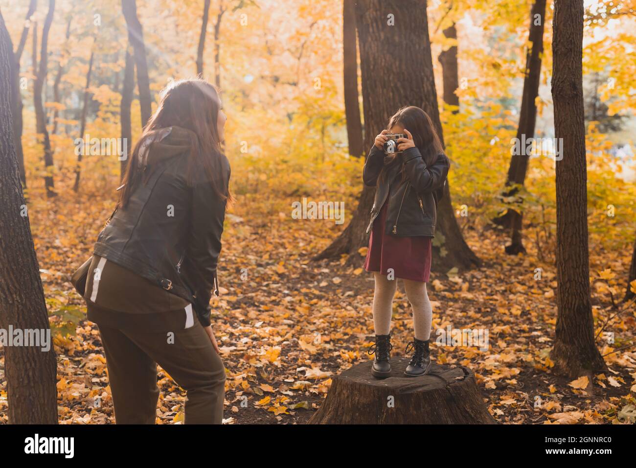 Child taking picture her mother on retro camera in autumn park. Hobbies ...
