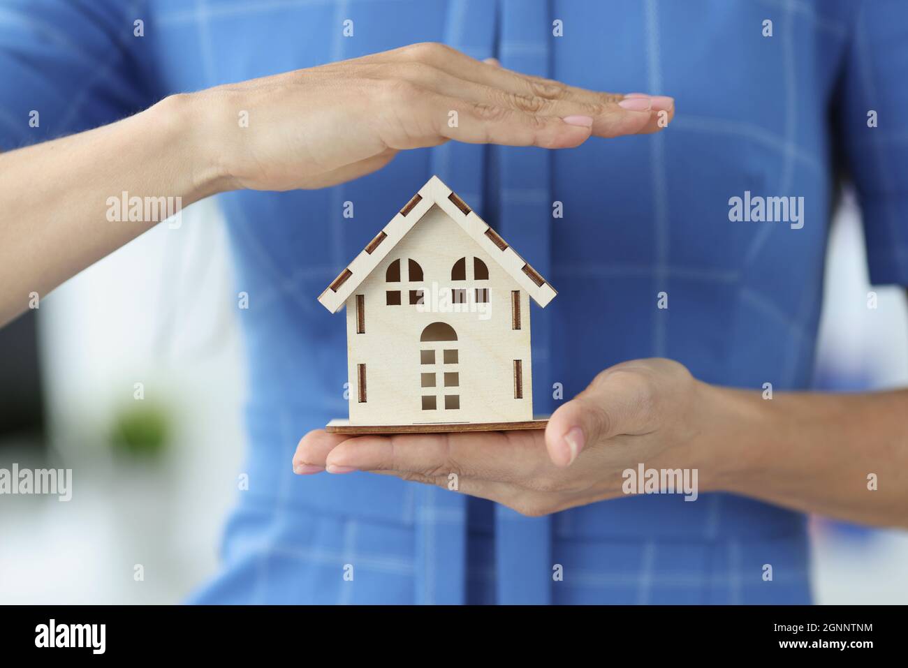 Female insurance agent is holding wooden house Stock Photo - Alamy