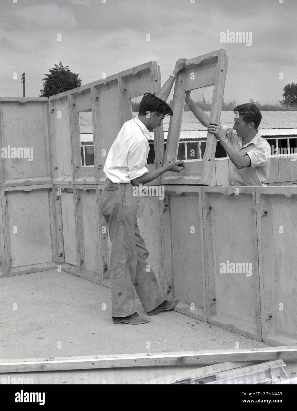 1960s, historical, constructing a prefab garage on an industrial ...
