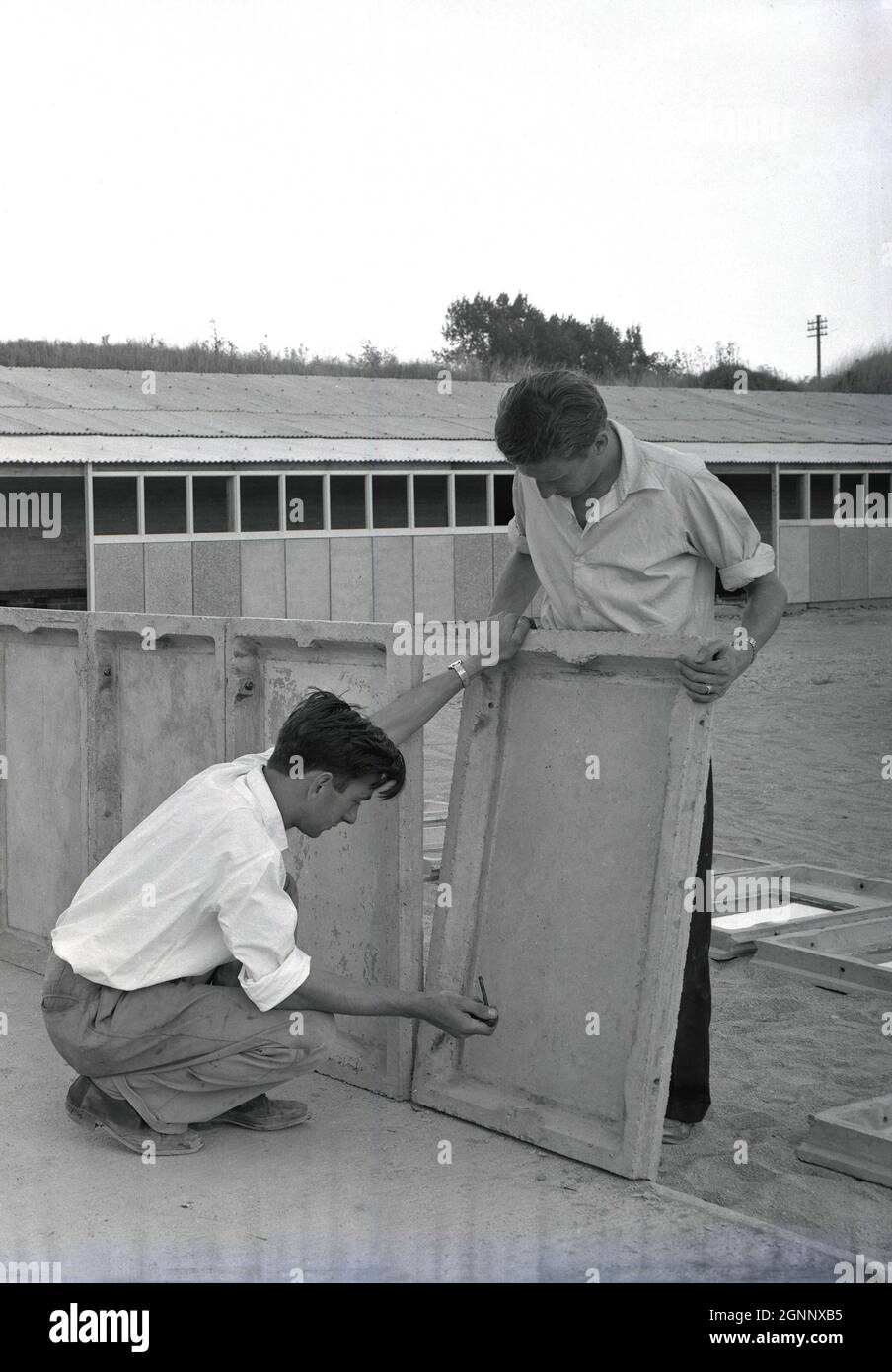 1960s, historical, constructing a prefab garage on an industrial ...