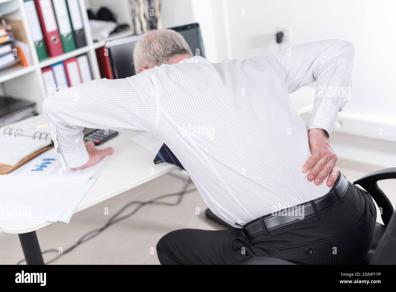 Businessman suffering from back pain at office Stock Photo - Alamy