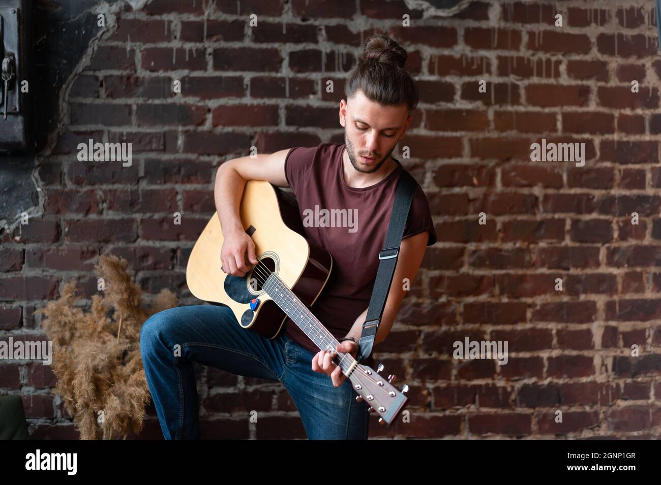 Man with acoustic guitar leaning brick wall playing music singing songs ...