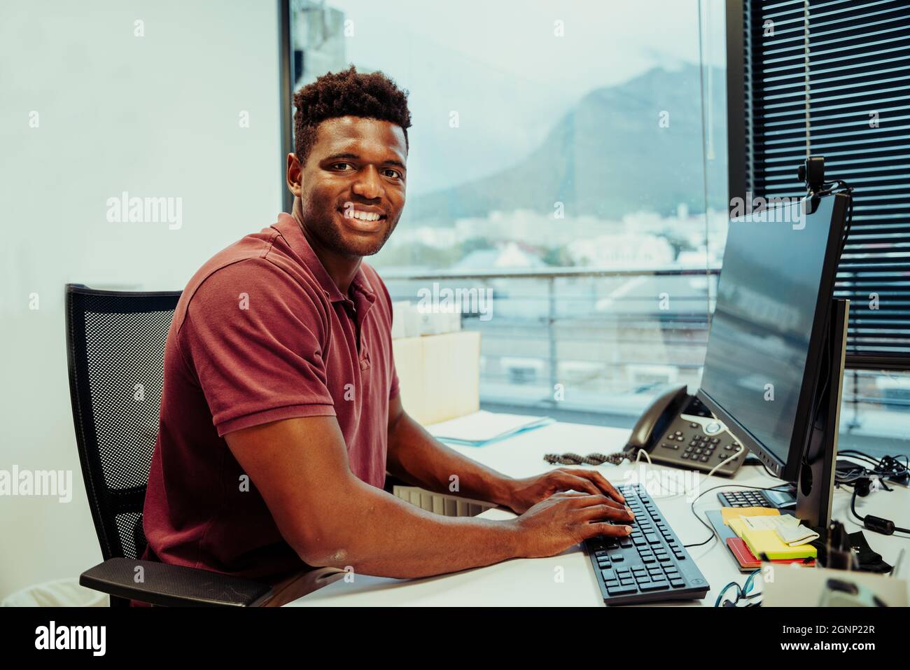 Mixed race male designer smiling while researching through layout ...
